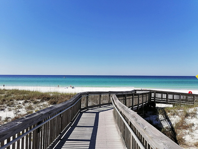 A wooden boardwalk winds through protective dunes at Henderson Beach State Park, leading visitors to the breathtaking emerald waters of the Gulf.