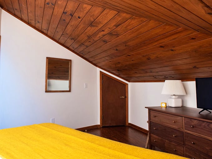 Simple elegance defines the sleeping quarters, where sloped wooden ceilings create a cozy nest after days filled with sunshine and salt air.