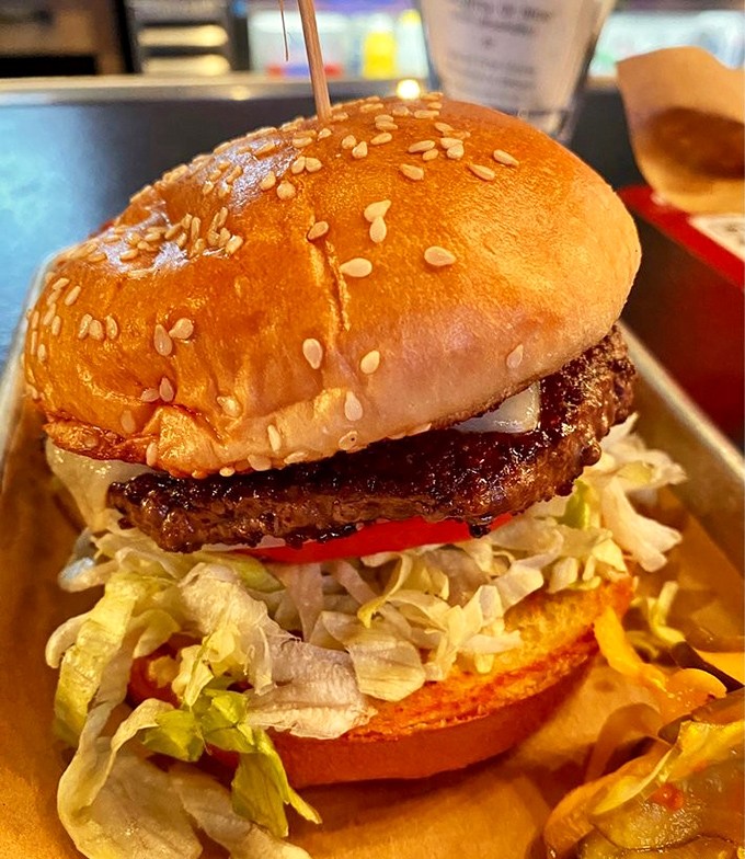 The Bluetick Burger with white cheddar sits pretty on its metal tray &ndash; a study in contrasts with crisp lettuce and a pillowy bun.