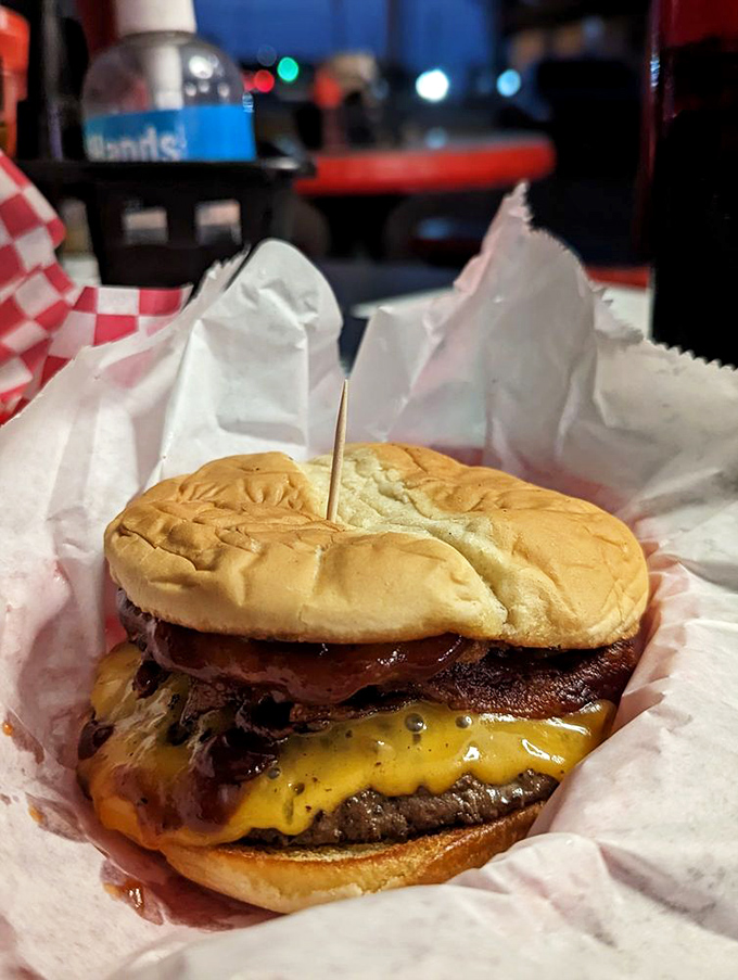 Melted cheese cascades down the sides of this burger like a yellow waterfall of flavor, promising a messy but magnificent eating experience.