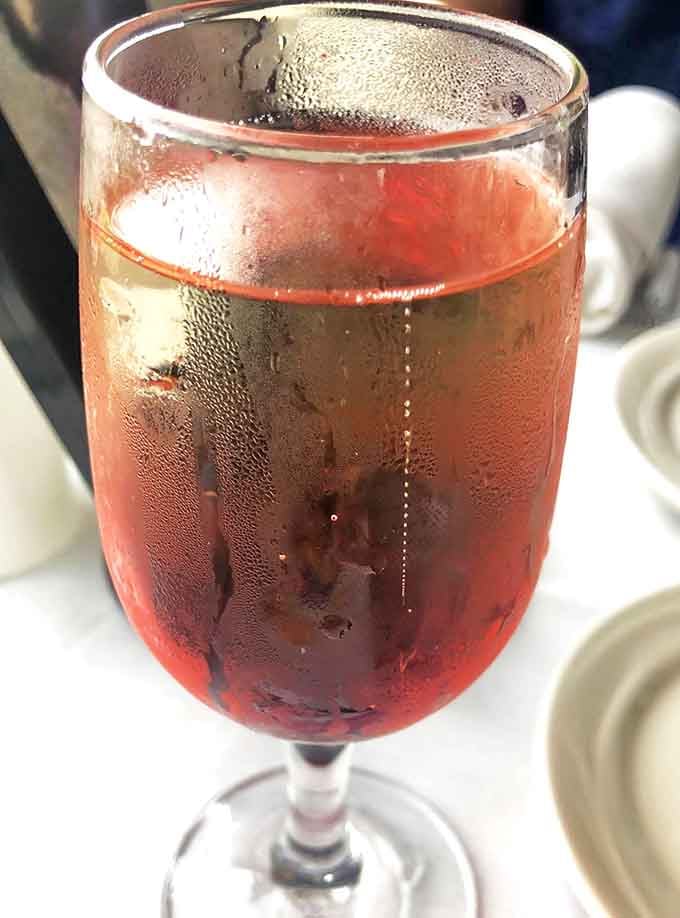 A glass of ros&eacute; catches the light like a clue hiding in plain sight, its rosy hue complementing the sunset view.