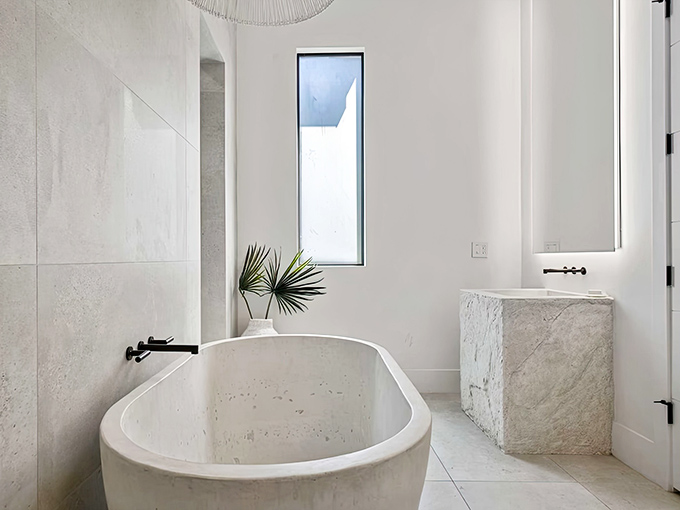 Minimalist luxury defines this stone bathtub sanctuary, where clean lines and natural materials create a spa-worthy retreat.