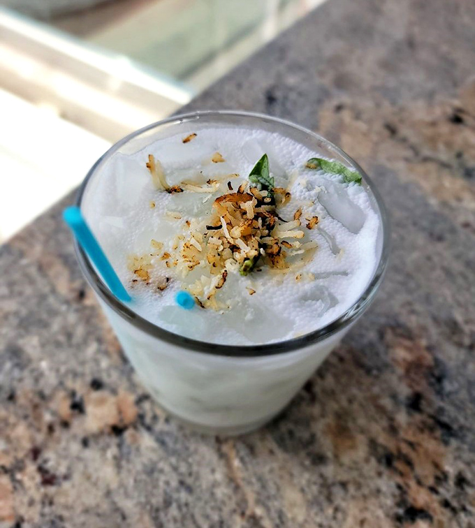 The Coconut Breeze cocktail &ndash; because sometimes vacation needs to come in liquid form. That toasted coconut rim isn't just garnish; it's a commitment to excellence.