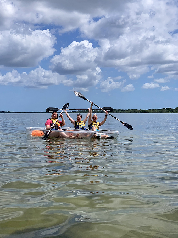 Three adventurers celebrate their conquest of the waters, paddles raised like knights of the aquatic round table.