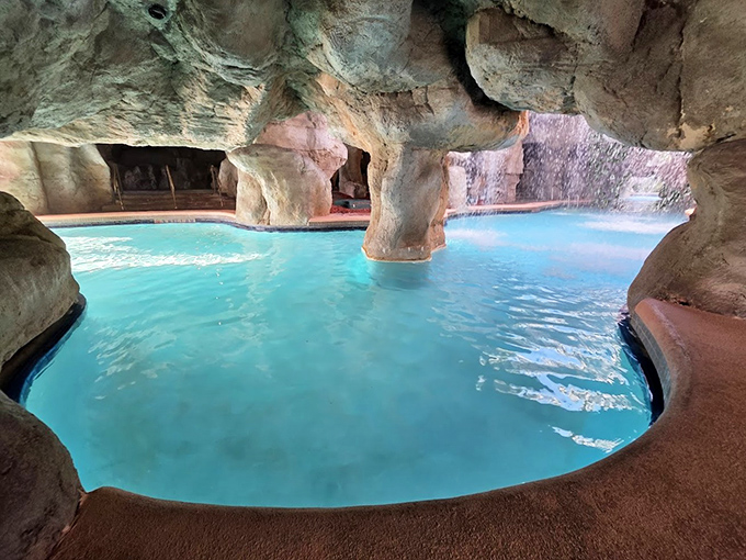 The grotto's interior reveals intimate swimming spaces where water cascades from above, nature's perfect air conditioning.