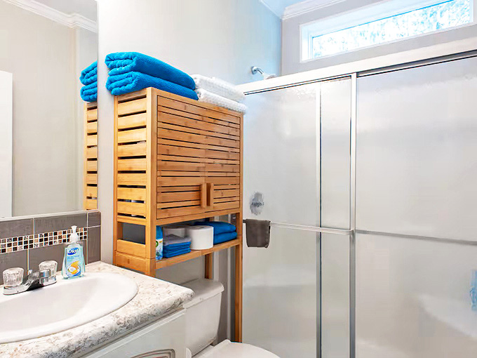 The bathroom combines functionality with style, featuring wooden storage solutions that bring warmth to the clean, contemporary space.