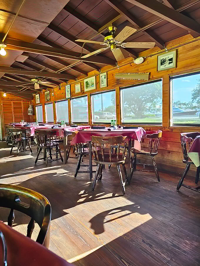Sunlight streams through windows onto wooden floors and burgundy tablecloths, creating the kind of natural ambiance no designer could replicate.