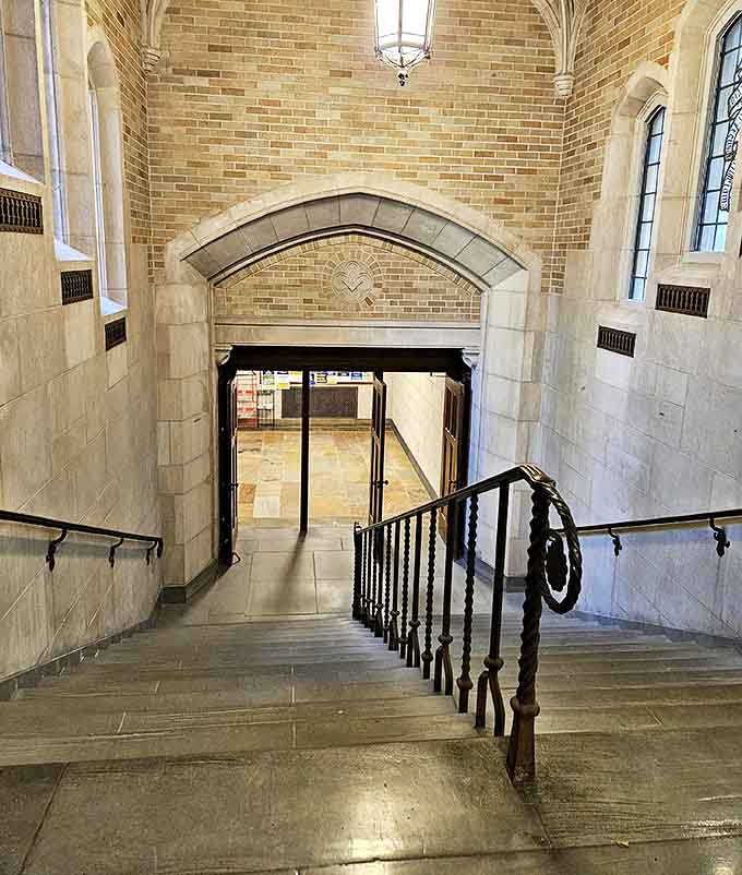 This elegant staircase descends beneath a vaulted ceiling, its wrought iron railing spiraling downward like a path to scholarly enlightenment.