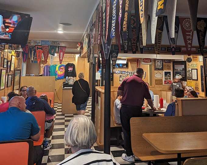 The dining room buzzes with conversation as regulars and newcomers alike gather under a canopy of college pennants and local memorabilia.