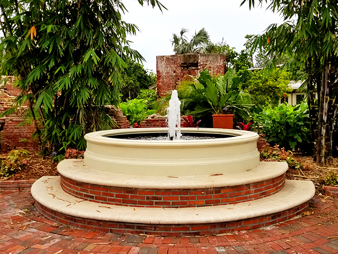Circular perfection in white and brick &ndash; this fountain creates a mesmerizing focal point amid the garden's organic shapes.
