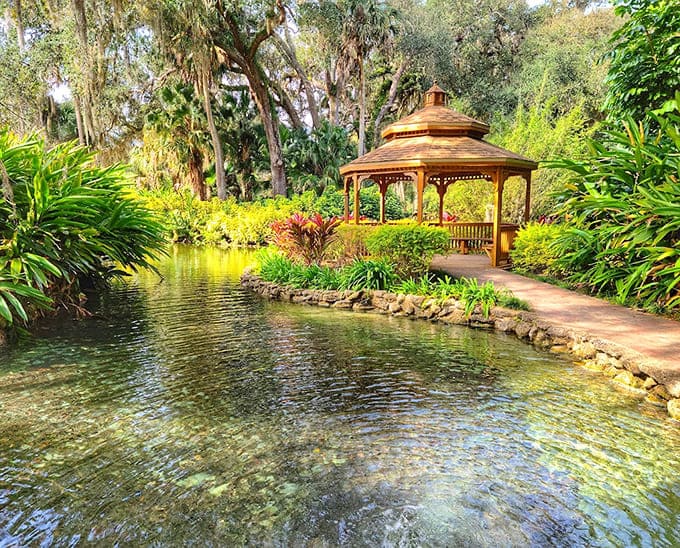 Formal gardens showcase colorful blooms and a peaceful pond that reflects the sky like nature's own mirror.
