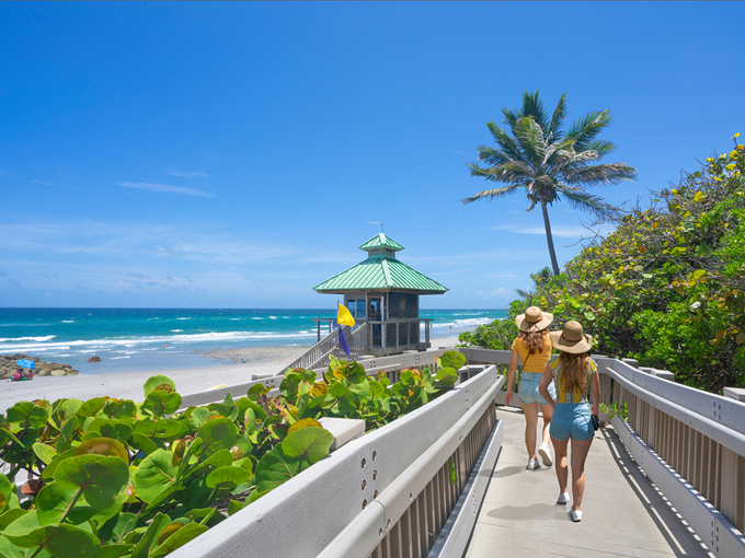 women,walking,on,boardwalk,to,beautiful,florida,beach.,girls,on