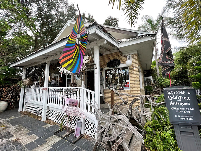 A charming yellow brick cottage with a welcoming white porch, colorful windsocks, and weathered wood sculptures &ndash; the perfect home for treasures both odd and antique.