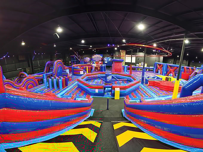 A bouncy wonderland of red and blue inflatables stretches across the massive indoor space, promising gravity-defying adventures for all ages.