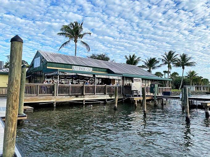 Riverside Cafe stands proudly on stilts above the water, its weathered green roof and wooden deck promising authentic Florida charm without pretension.