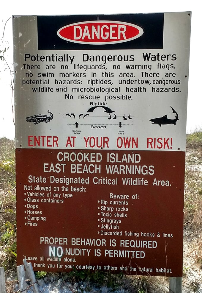Warning signs serve as both caution and unintentional advertisement for the wild, untamed nature that makes Crooked Island Beach so refreshingly different from commercial shores.