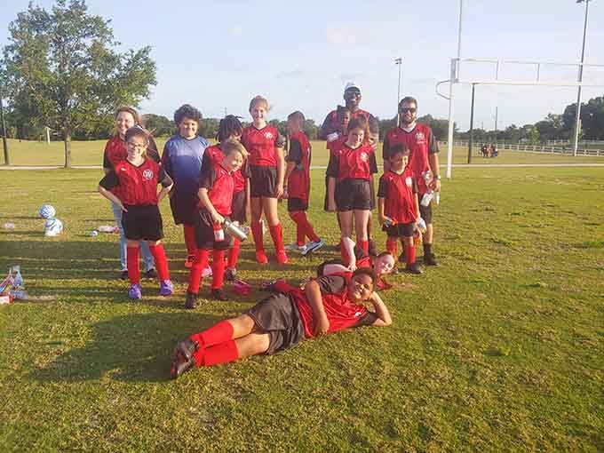 Young athletes in their game-day red, learning life lessons about winning, losing, and why you should always tie your cleats properly before kickoff.
