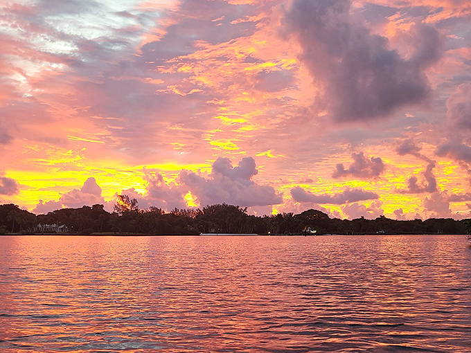 The sky performs its nightly masterpiece, painting clouds in impossible shades of pink and gold across the refuge waters.