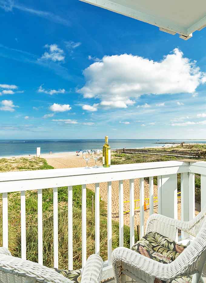 Enjoy a stunning elevated view of the coastline from a white balcony, the perfect spot for sipping and soaking in scenery.