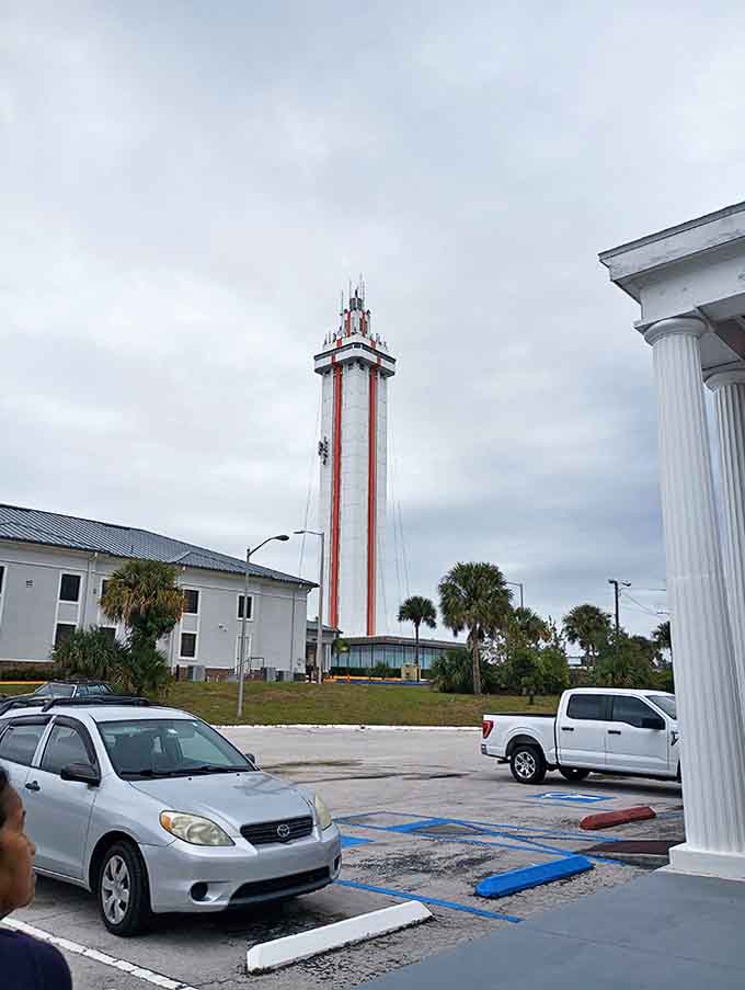 Tower and Parking: Surrounded by palm trees and Florida sunshine, the tower rises dramatically from its parking area, a stark white exclamation against the blue sky.