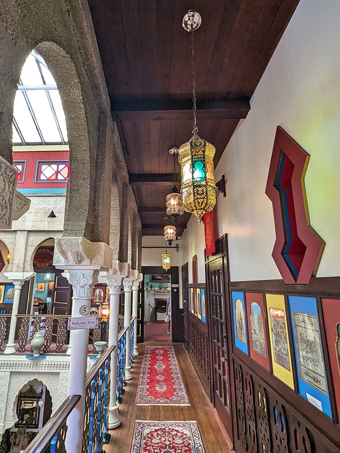 The upper balcony offers views of the courtyard below, with ornate railings and hanging lanterns that create an enchanting atmosphere throughout.
