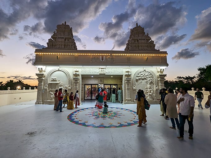 As evening falls, visitors gather at the temple entrance, their colorful attire creating a human kaleidoscope against the stone backdrop.