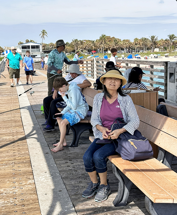 Visitors of all ages find their perfect spot on the pier's benches, where watching the world go by becomes an art form.