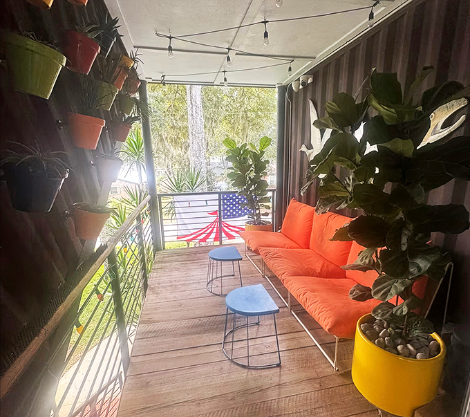 Lush plants and vibrant orange seating create an outdoor oasis where Florida's sunshine feels even warmer against industrial steel.