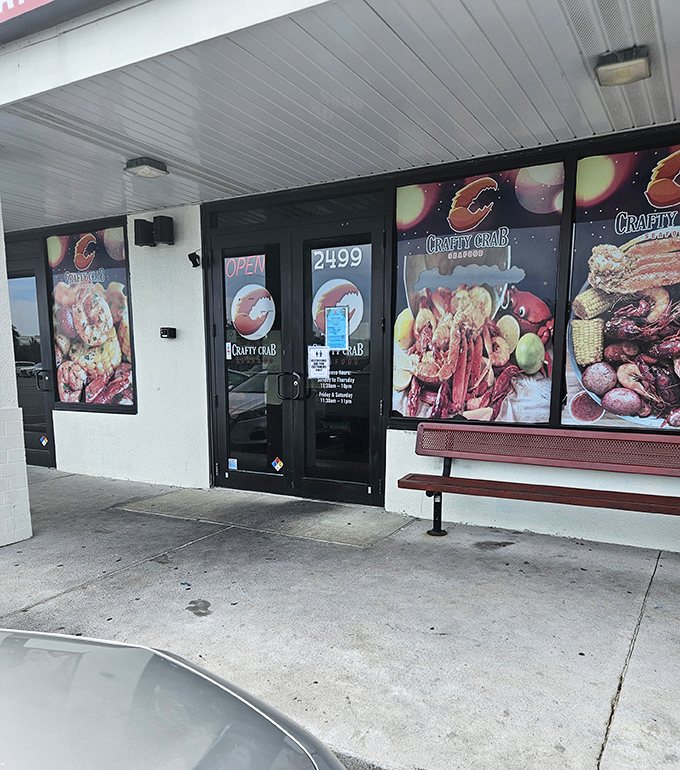 Crafty Crab's storefront showcases colorful images of their seafood specialties. The simple bench outside offers a spot to rest while waiting for a table.