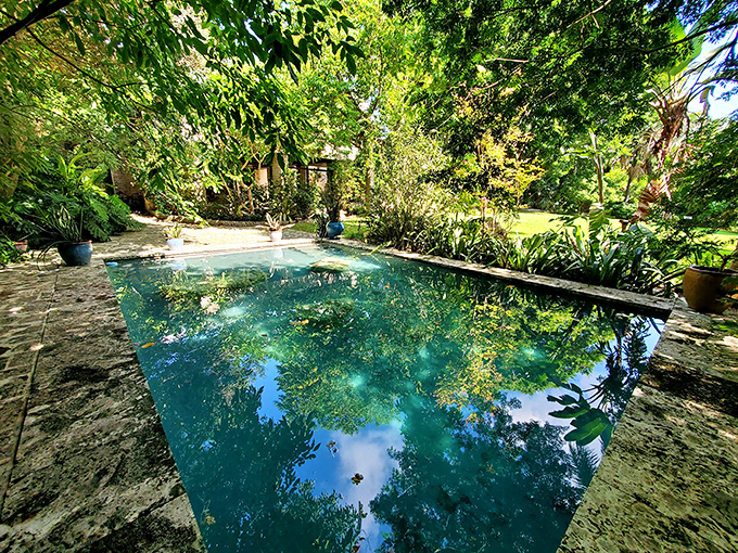 A serene reflecting pool mirrors the surrounding tropical foliage, creating a perfect symmetry between water and sky.
