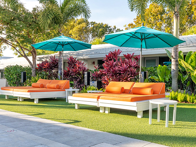 Orange cushions pop against crisp white loungers, creating the perfect perch for sunshine sipping and paperback page-turning.