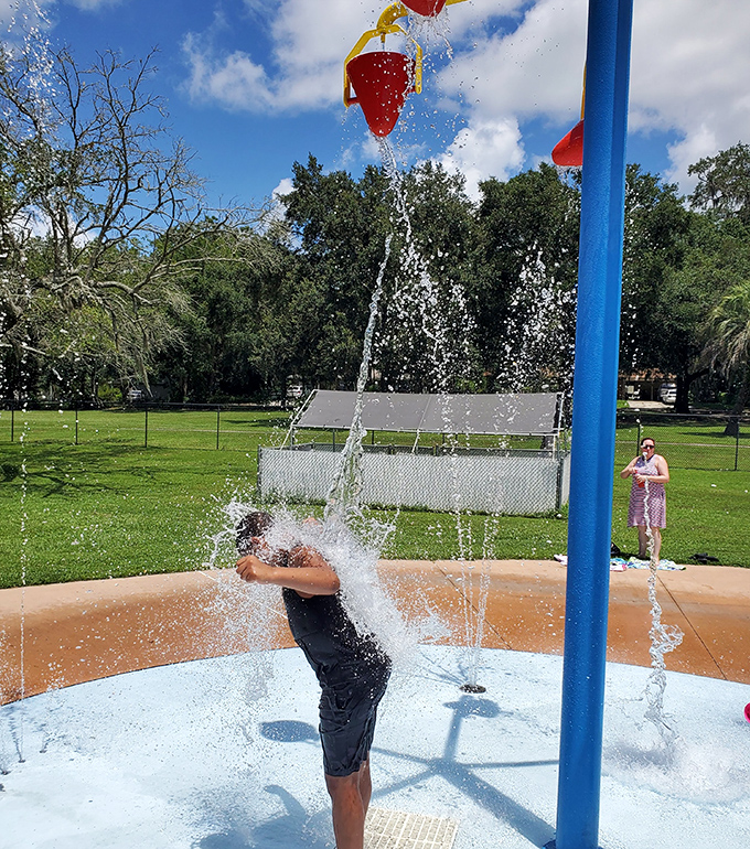 Water buckets tip to create dramatic splashes, the anticipation building as children gather below for nature's most refreshing surprise party.