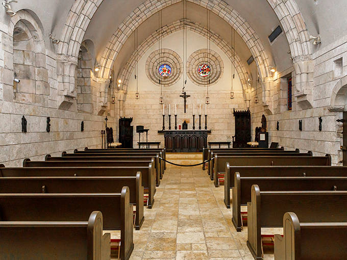 The Ancient Spanish Monastery's stone chapel interior features soaring arched ceilings and peaceful rows of wooden pews.