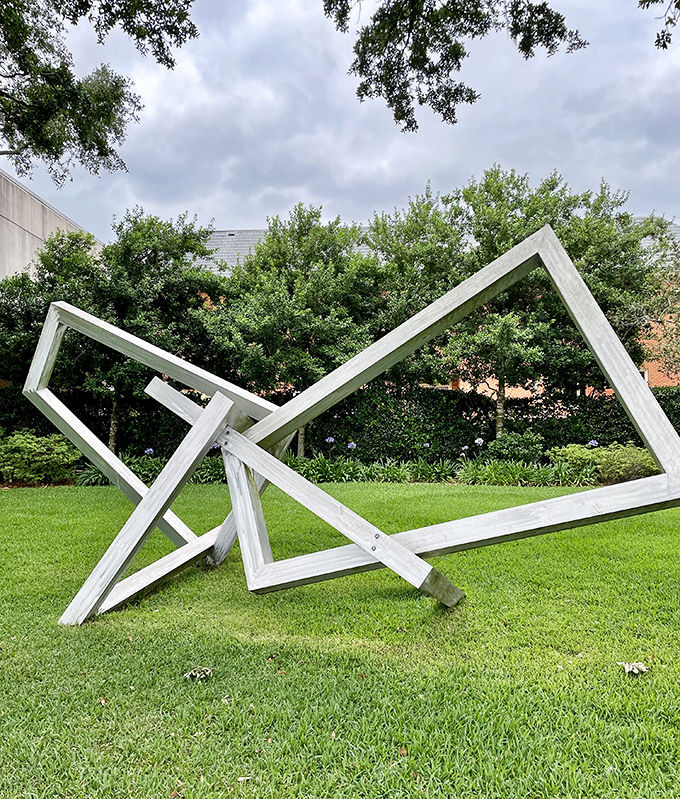 White geometric frames collapsed in artistic rebellion &ndash; or perhaps just taking a well-deserved rest on the lawn.