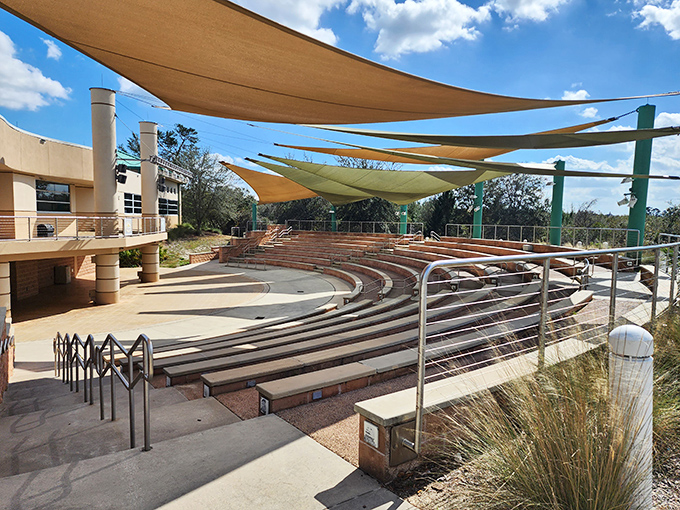 The outdoor amphitheater creates nature's classroom, where presentations unfold beneath fabric sails dancing in Florida breezes.