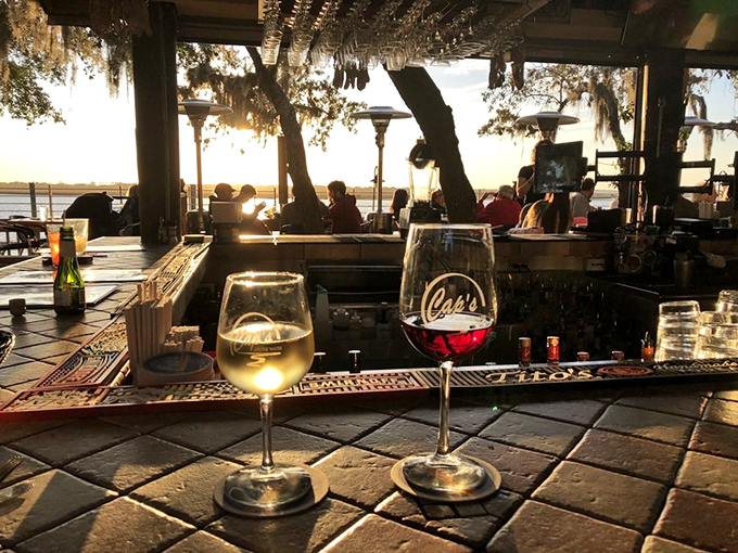 Sunset transforms Cap's bar into a magical space where wine glasses capture the day's fading light and conversations flow freely.