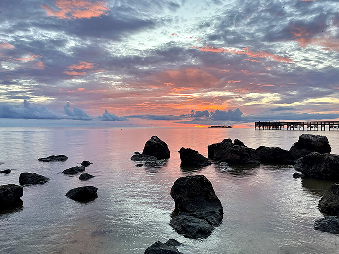 A sunset painting the Gulf waters in shades of pink and orange, with rocky sentinels standing watch like nature's own theater seating.