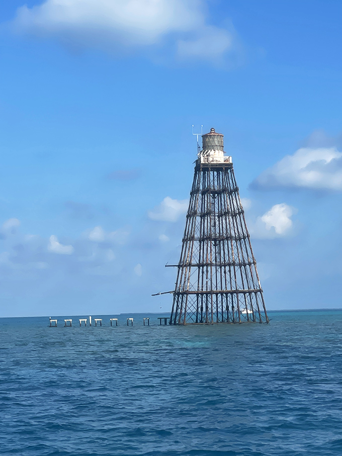 Sand Key Lighthouse rises from the ocean like a metal spider, surrounded by boats enjoying the crystal-clear waters of this offshore paradise.