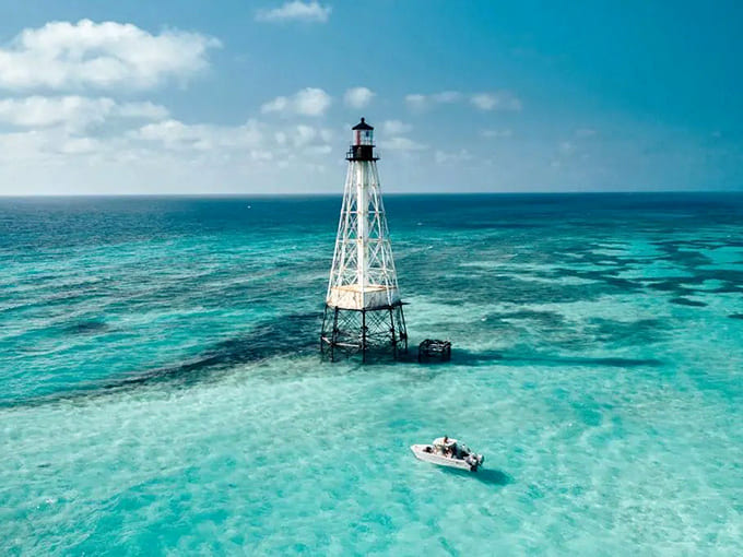 One boat, one lighthouse, and water so blue it looks fake; this is the kind of scene that makes you understand why people never leave.