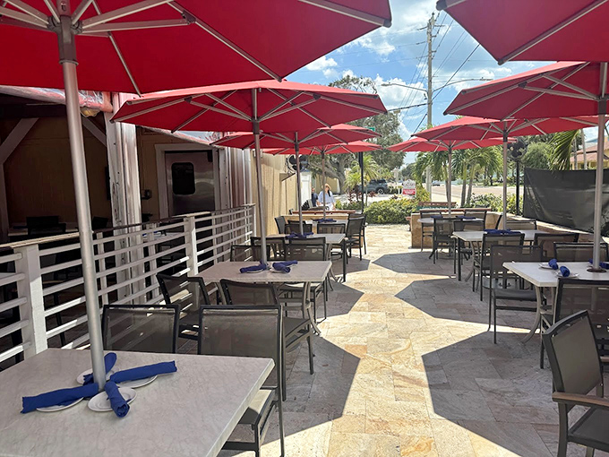 Red umbrellas create islands of shade on this stone terrace, where every table feels like the best seat in the house.
