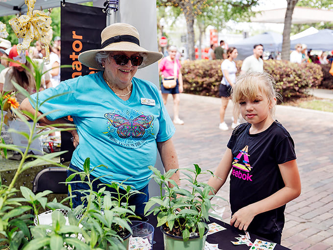 A volunteer helps a young visitor select the perfect plant, passing down gardening wisdom to the next generation of green thumbs.