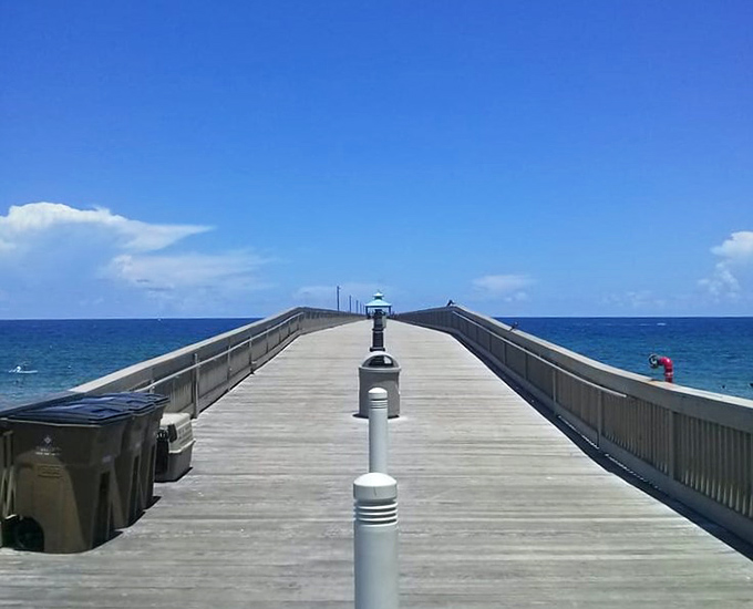 The pier stretches toward the horizon like a wooden runway, launching dreams into the endless blue beyond.