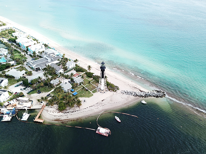 A postcard-perfect scene from above reveals the lighthouse's strategic position between emerald Intracoastal waters and the deep blue Atlantic.