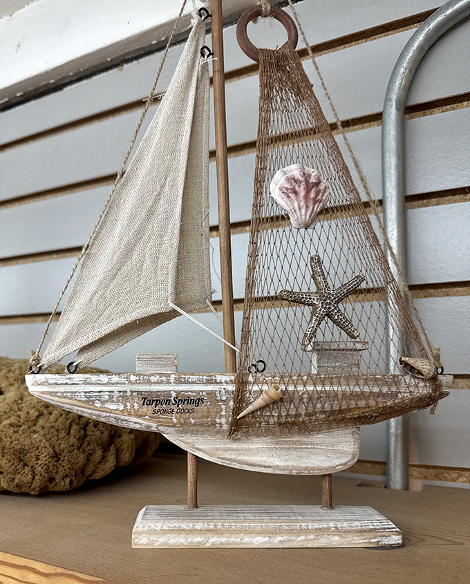 This decorative sailboat, adorned with shells and netting, captures the maritime spirit of Tarpon Springs in miniature souvenir form.