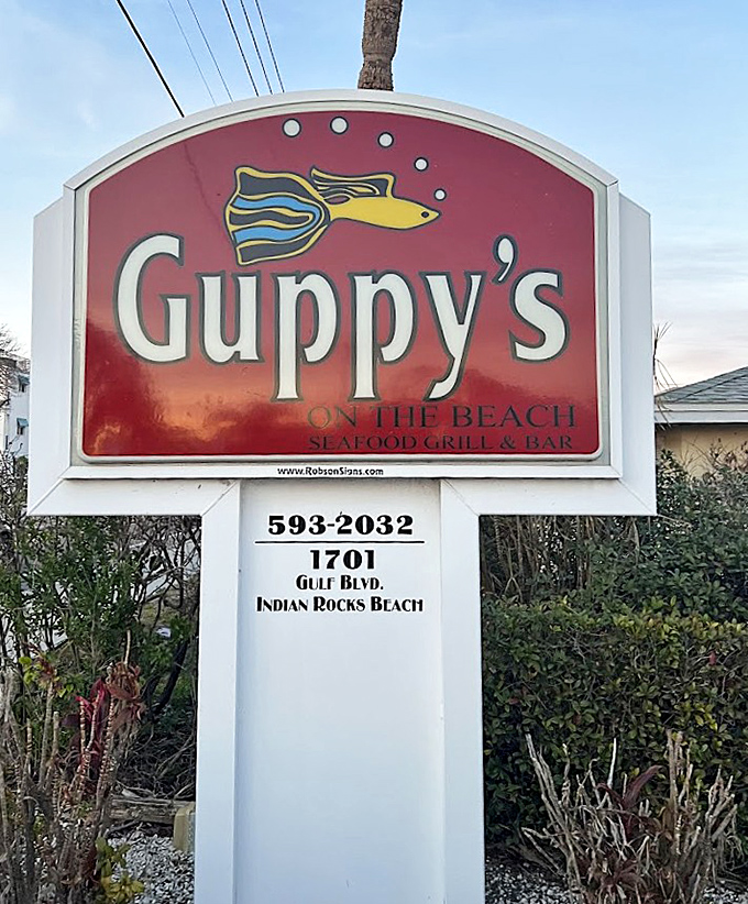 The cheerful guppy mascot grins from this sign, like a friendly local sharing directions to the best meal in town.
