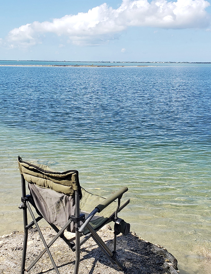 Beach therapy in session: where one folding chair, crystal waters, and uninterrupted horizon time heal what expensive spas cannot.