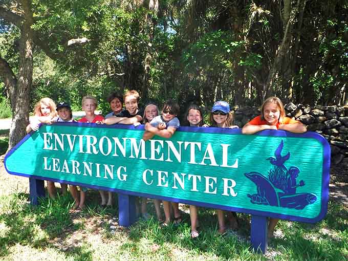 Kids proudly displaying the center's sign like they've just discovered the coolest secret clubhouse, which isn't far from the truth really.