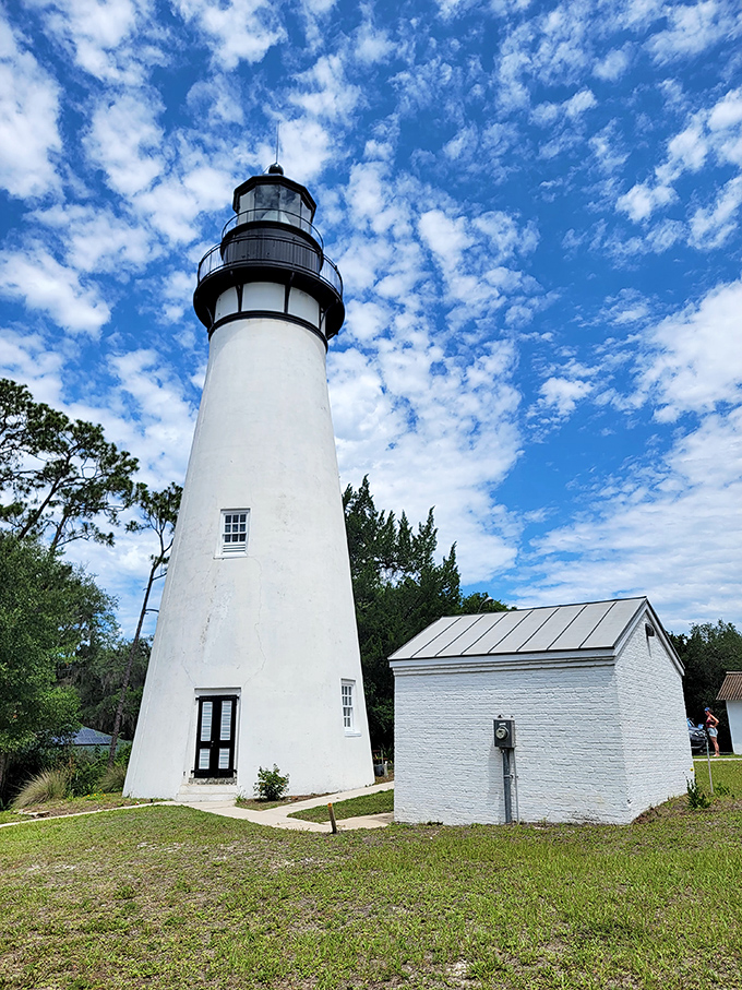 The classic white tower of Amelia Island Light stands proudly against a cloud-dotted blue sky, a timeless sentinel watching over Fernandina Beach.