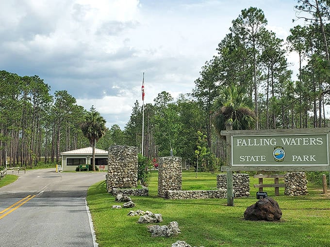 The entrance to Falling Waters State Park welcomes visitors with rustic stone pillars and lush greenery, promising natural wonders beyond.