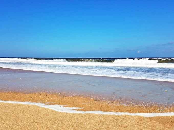 Crystal clear waves lap gently at the shore of Usina Beach, where the Atlantic meets pristine sand under a perfect blue sky.